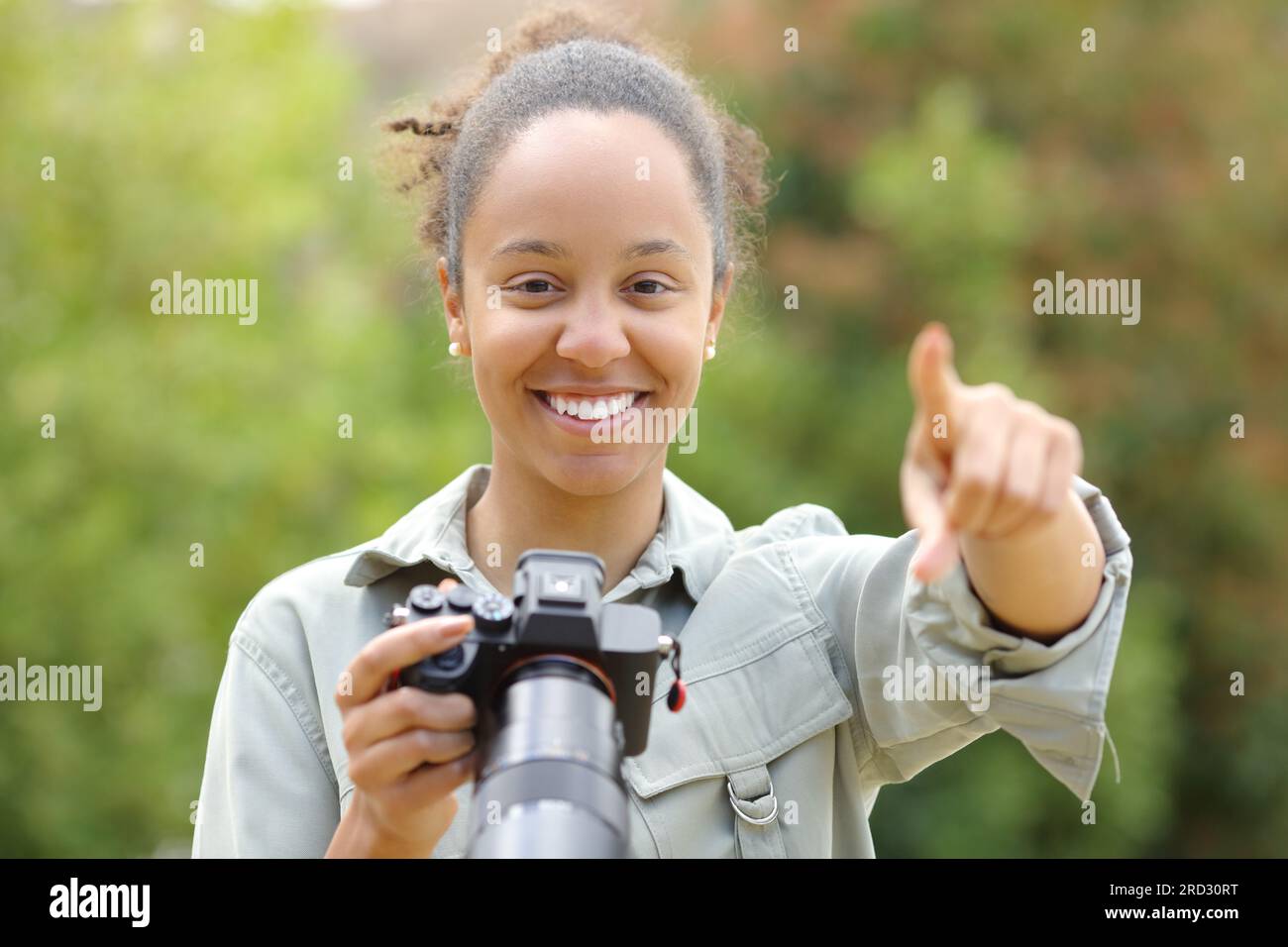Front view portrait of a black photographer pointing at camera holding ...