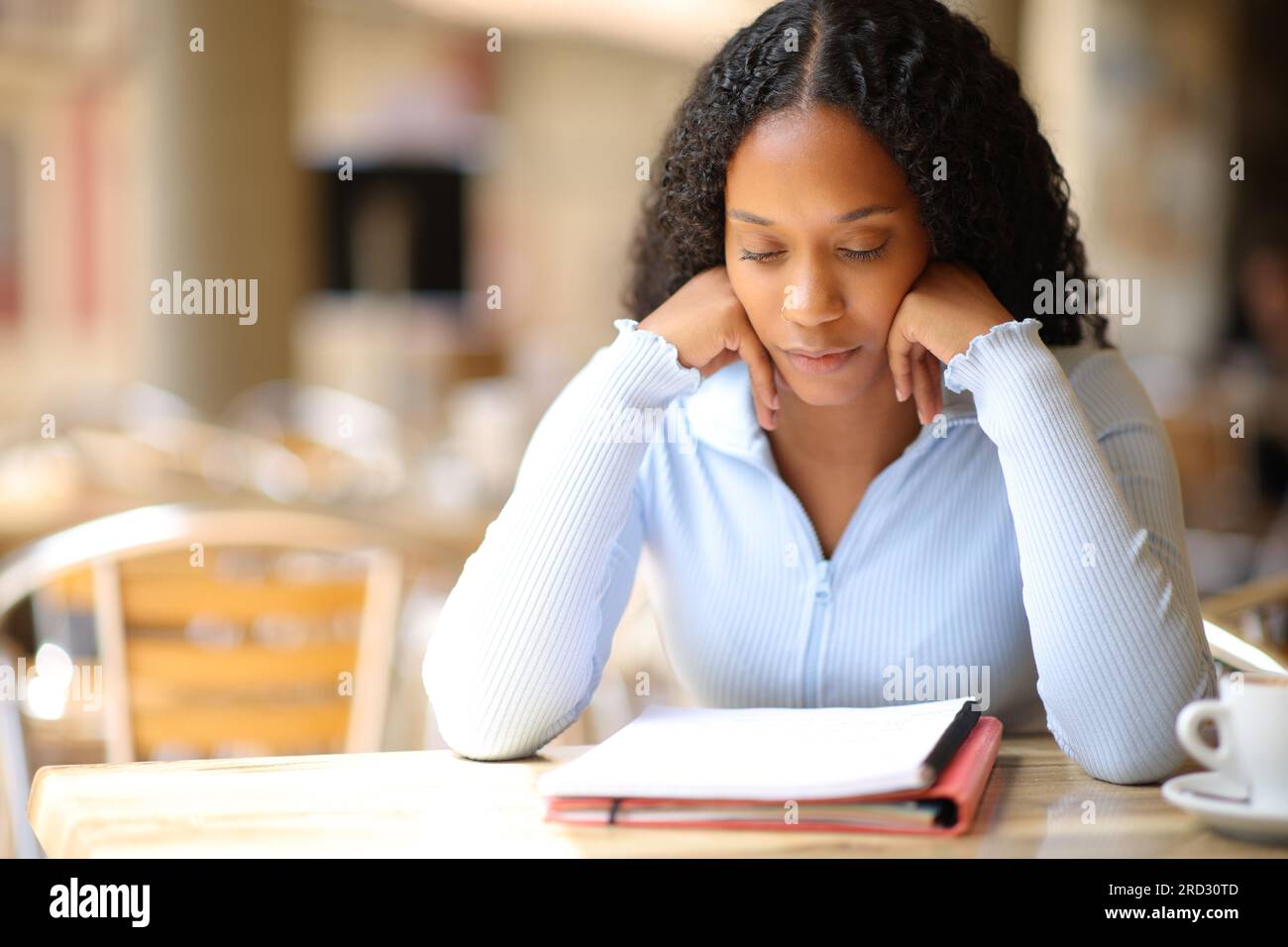Black woman studying memorizing notes from notebook in a coffee shop ...