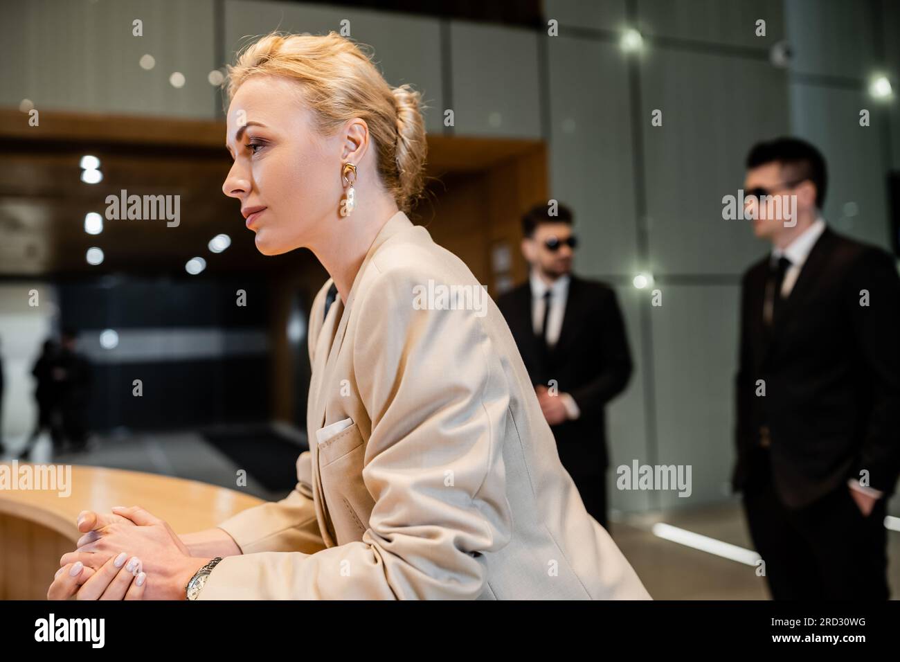 blonde woman in suit standing at reception desk, personal security ...