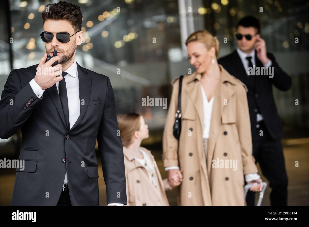 handsome bodyguard communicating through walkie talkie, standing next ...