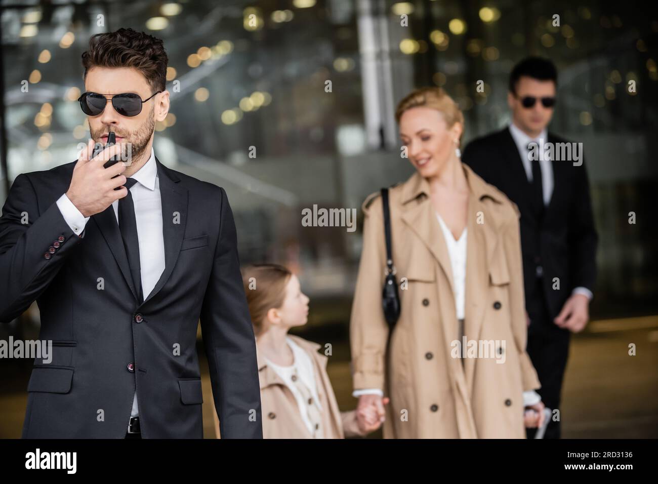 handsome bodyguard communicating through walkie talkie, standing next ...