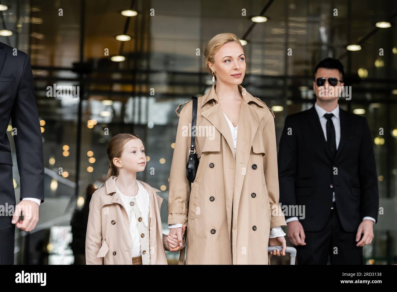 bodyguards walking next to blonde woman and preteen kid, entering hotel ...