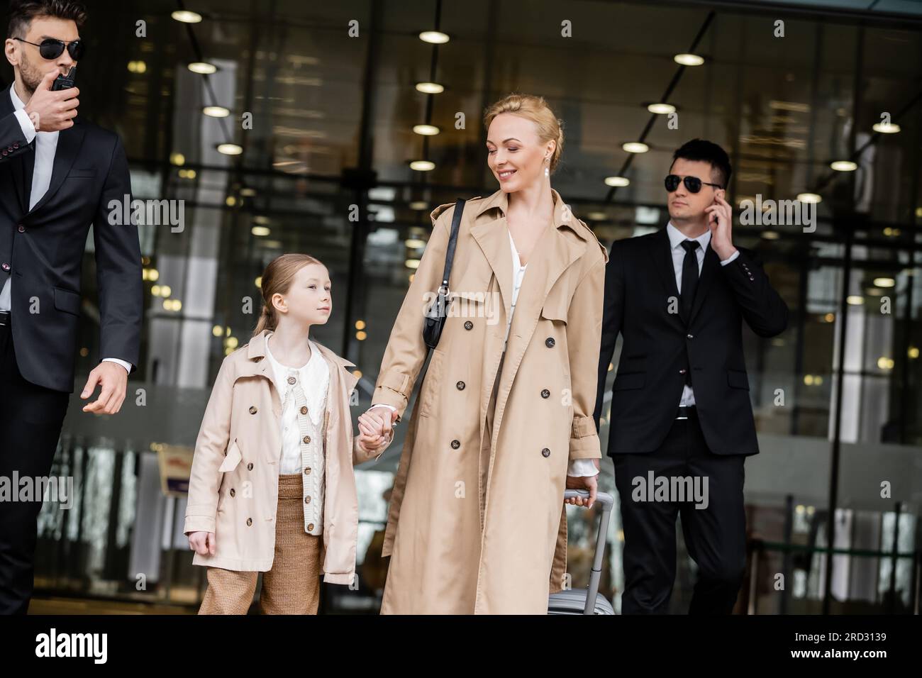 bodyguards communicating with each other next to happy woman and ...