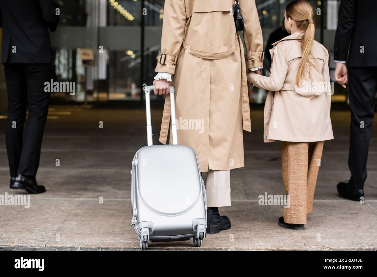 cropped view of bodyguards walking next to woman and preteen kid ...
