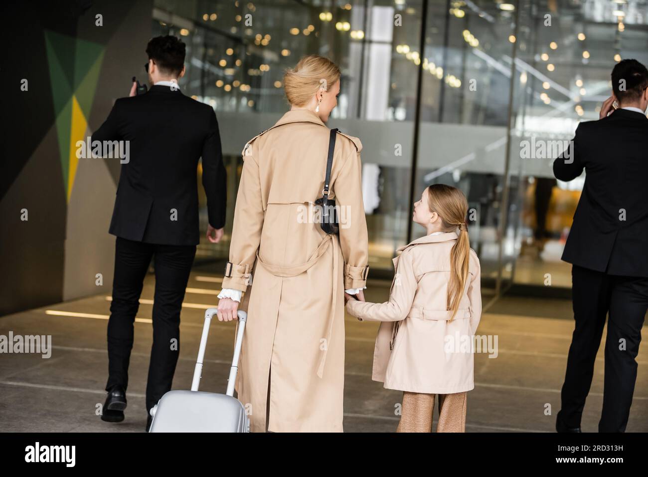 bodyguards walking next to blonde woman and preteen kid, entering hotel ...