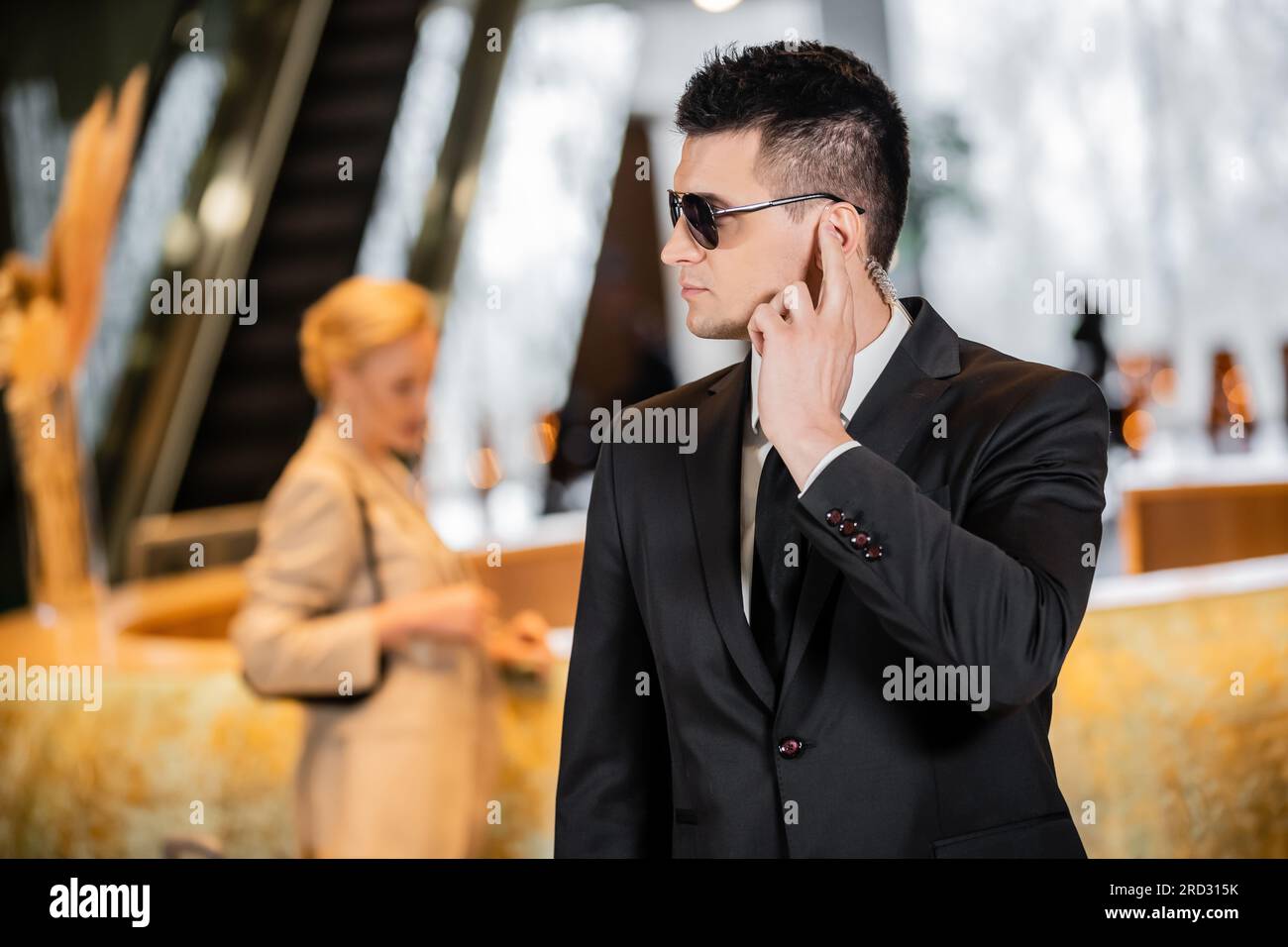 bodyguard concept, handsome man in formal wear and tie touching ...