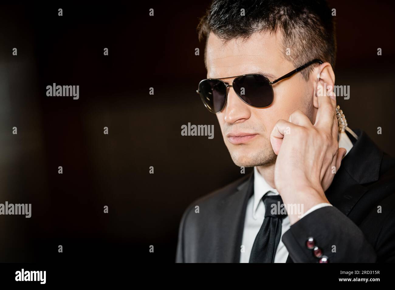 good looking bodyguard in sunglasses, handsome man in suit touching ...