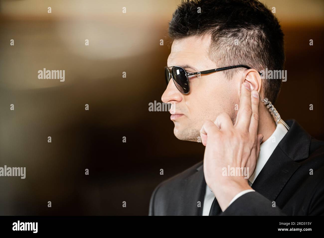 handsome bodyguard in sunglasses, handsome man in suit and tie touching ...