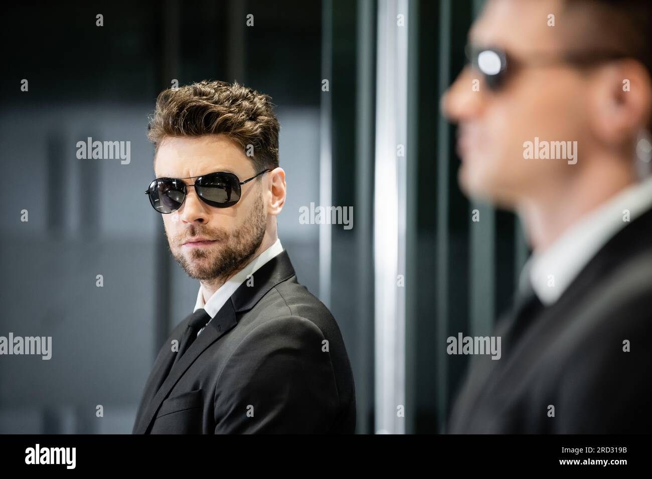 bodyguard service, private security, handsome man in suit and sunglasses standing in hotel lobby ...