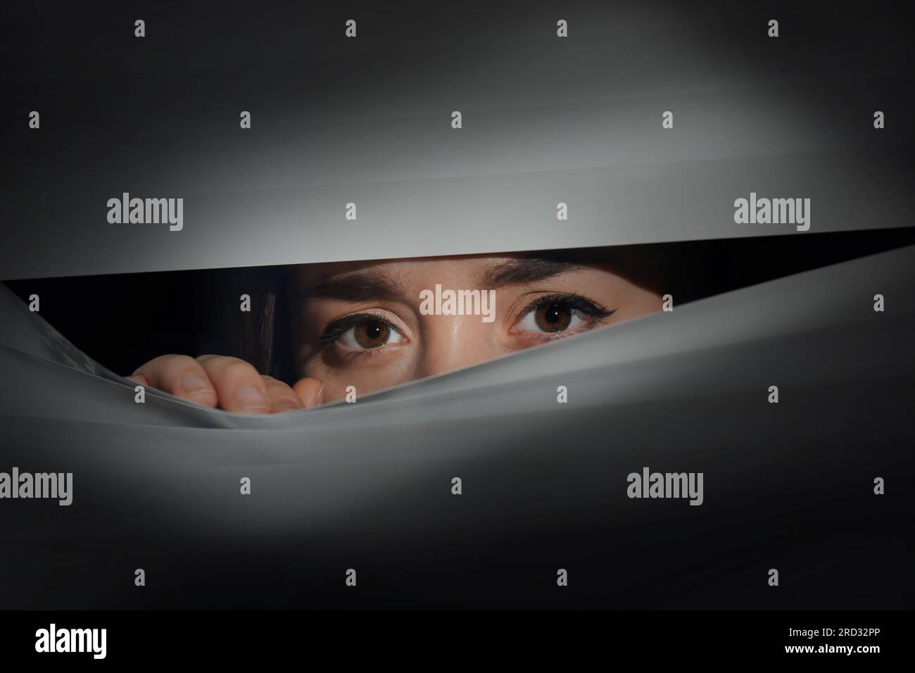 Worried woman looking through window blinds into darkness. Paranoia ...