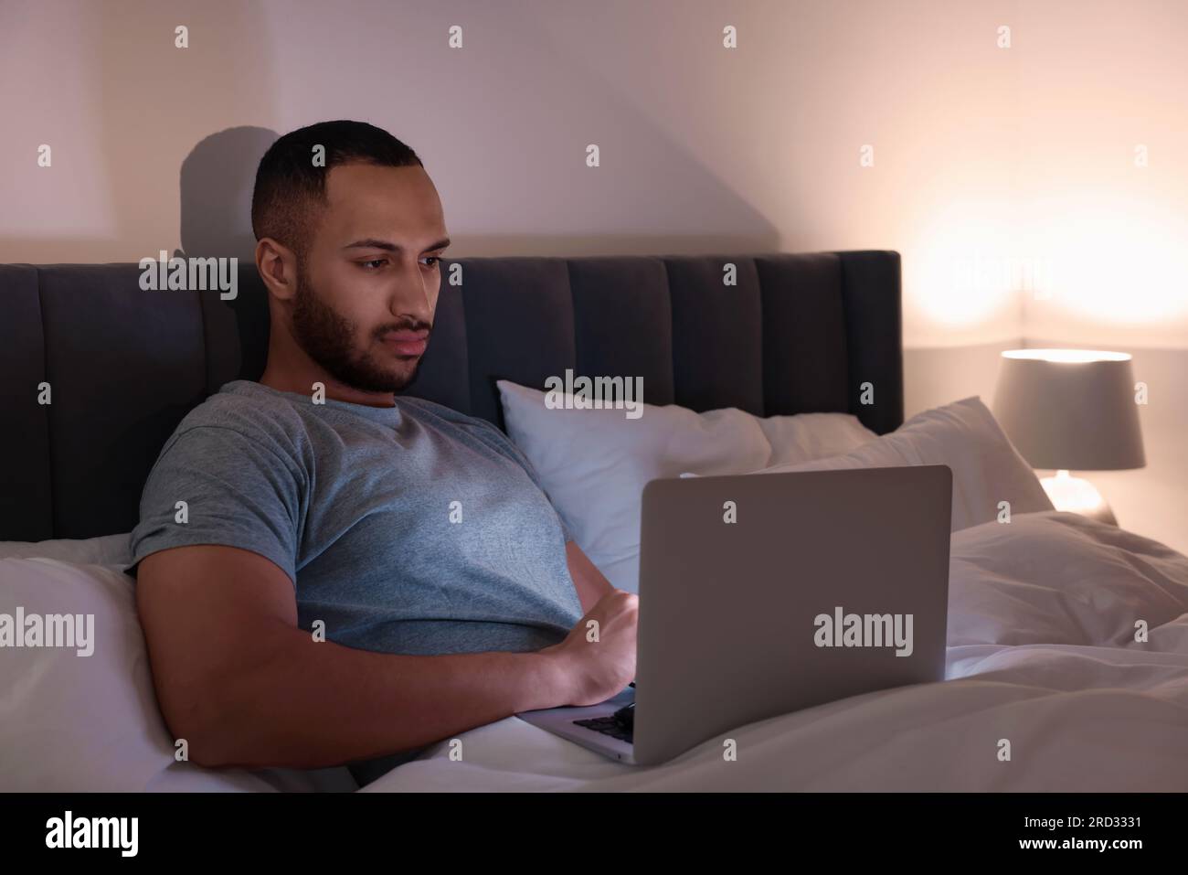 Young man using laptop in bed at night. Internet addiction Stock Photo ...