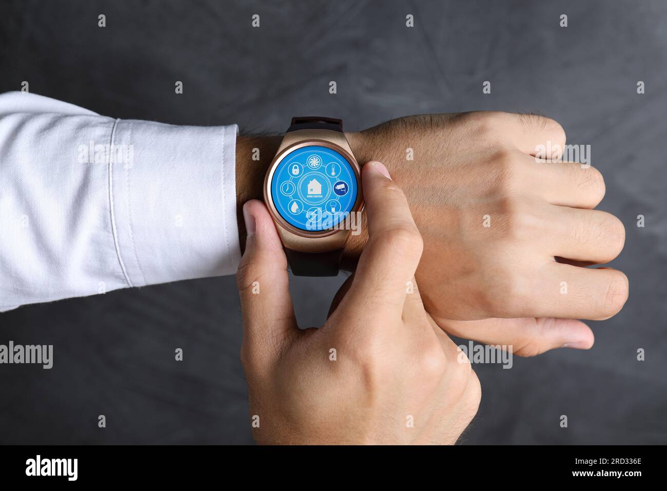 Man setting smart home control system via smartwatch against dark grey ...