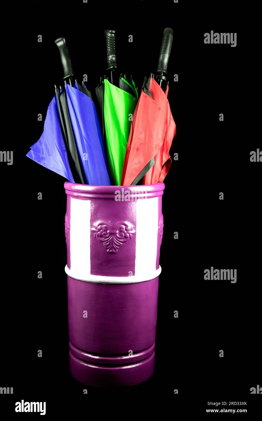 Coloured umbrellas in a painted earthenware umbrella stand isolated on ...