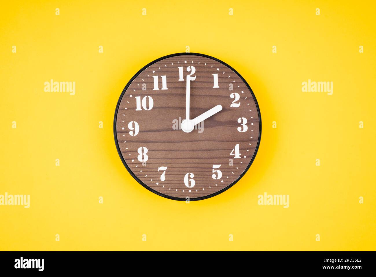 Retro wooden clock at 2 O' clock on yellow color background Stock Photo ...