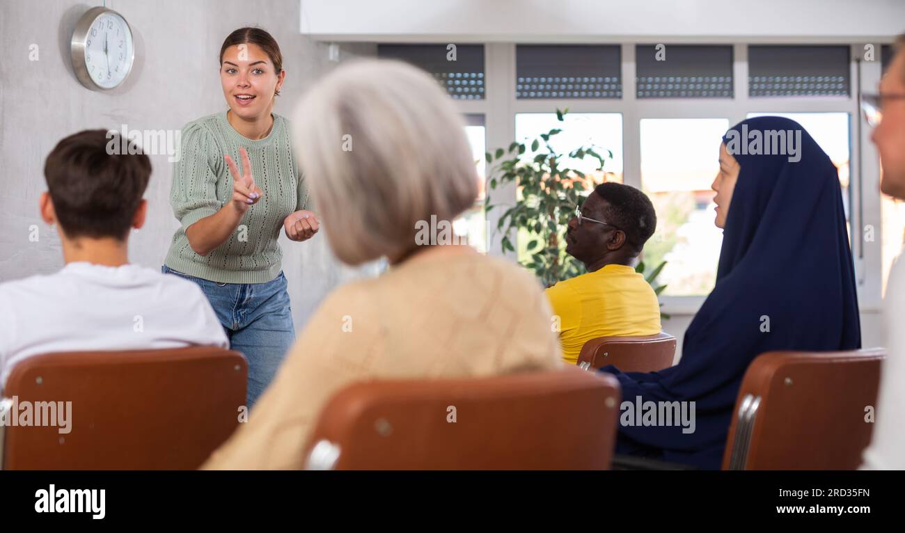 Young female teacher giving lecture to group of multinational students ...