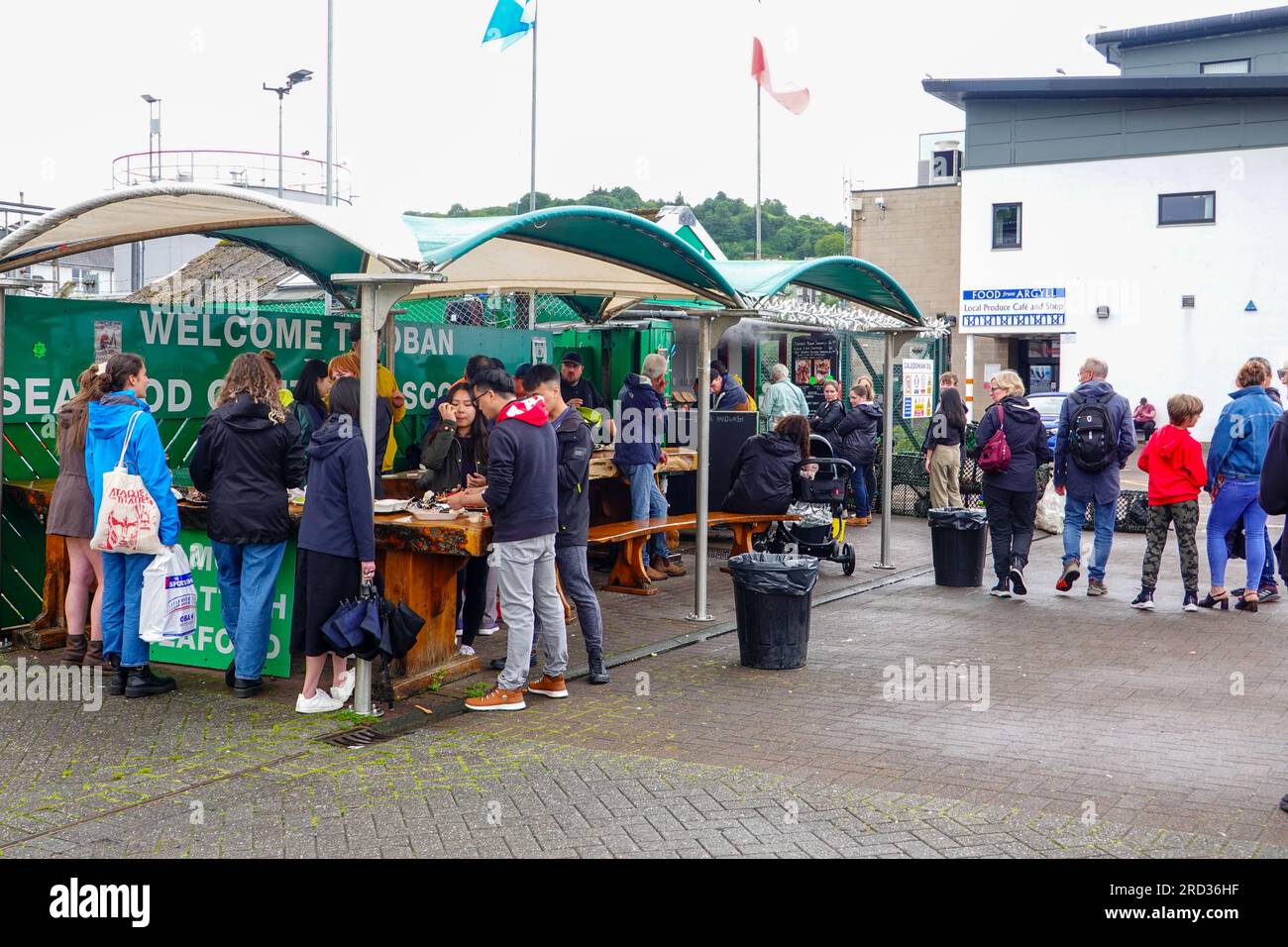 People standing and eating local Scottish seafood outside, Oban Seafood ...