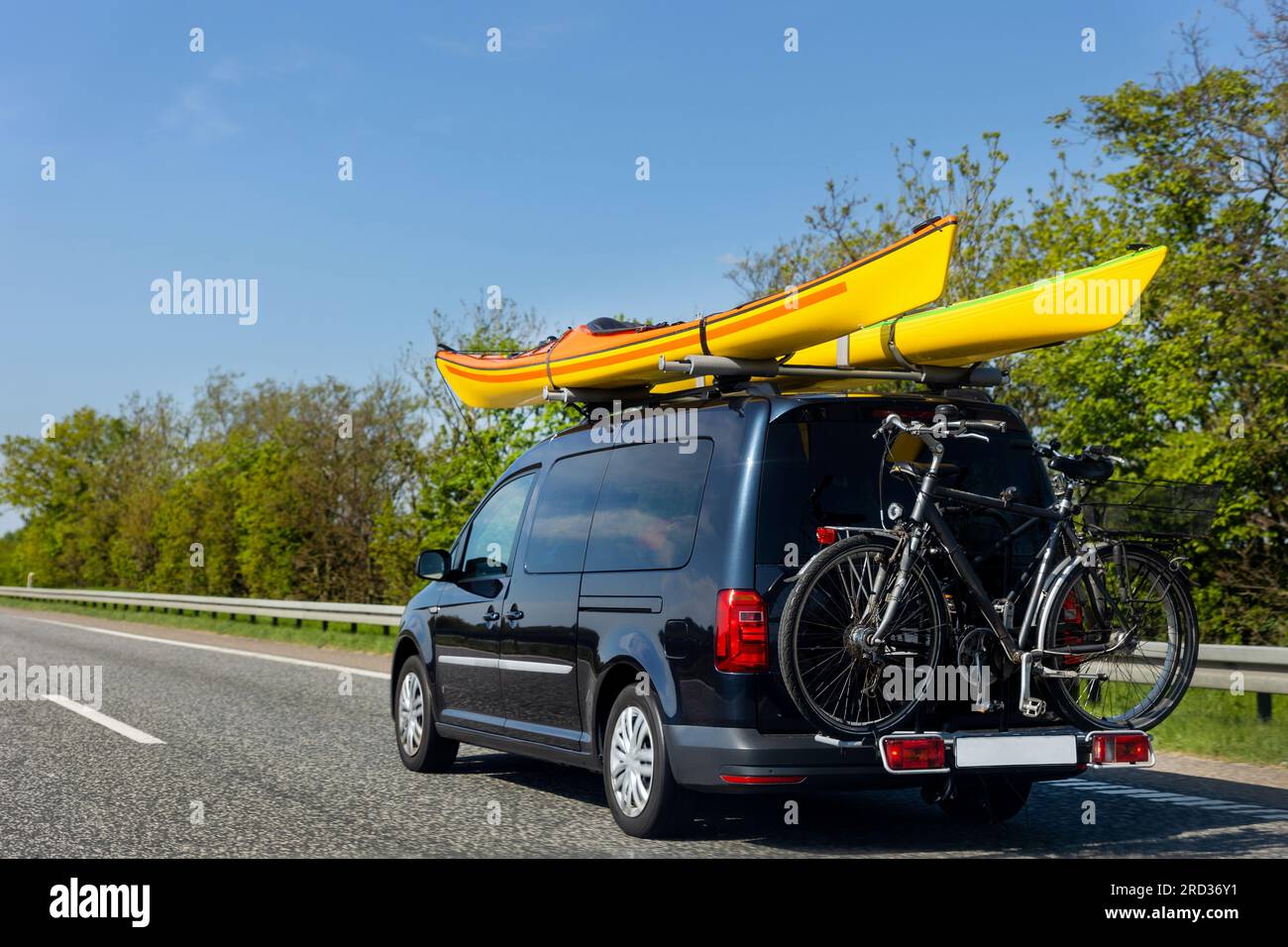 Back view modern black family wagon van car with mounted roof kayak and ...