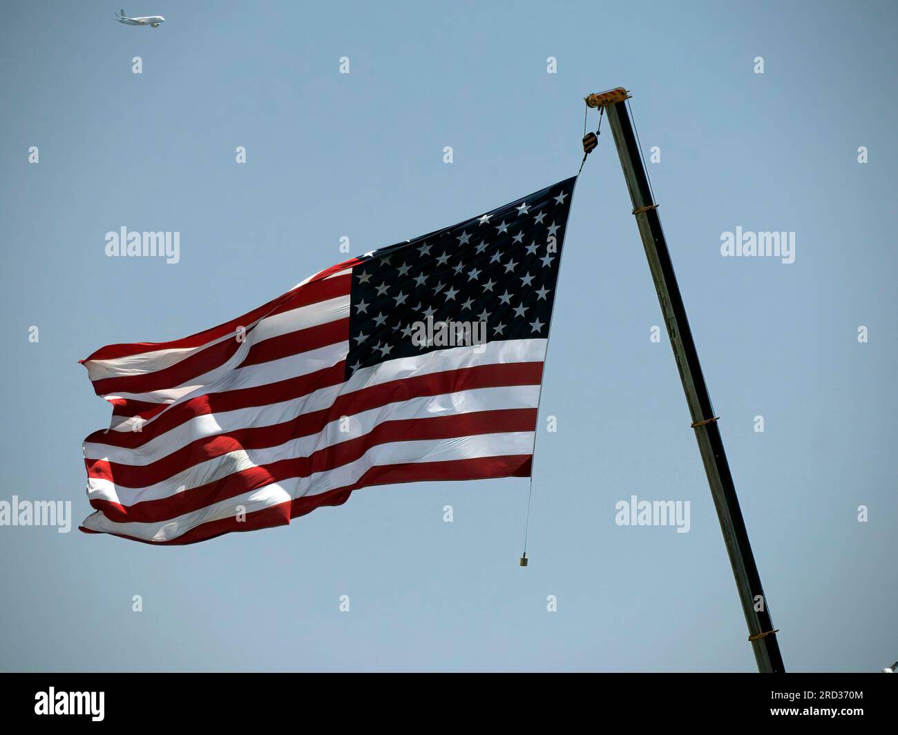 American flag against a blue clear sky and an airplane Stock Photo - Alamy