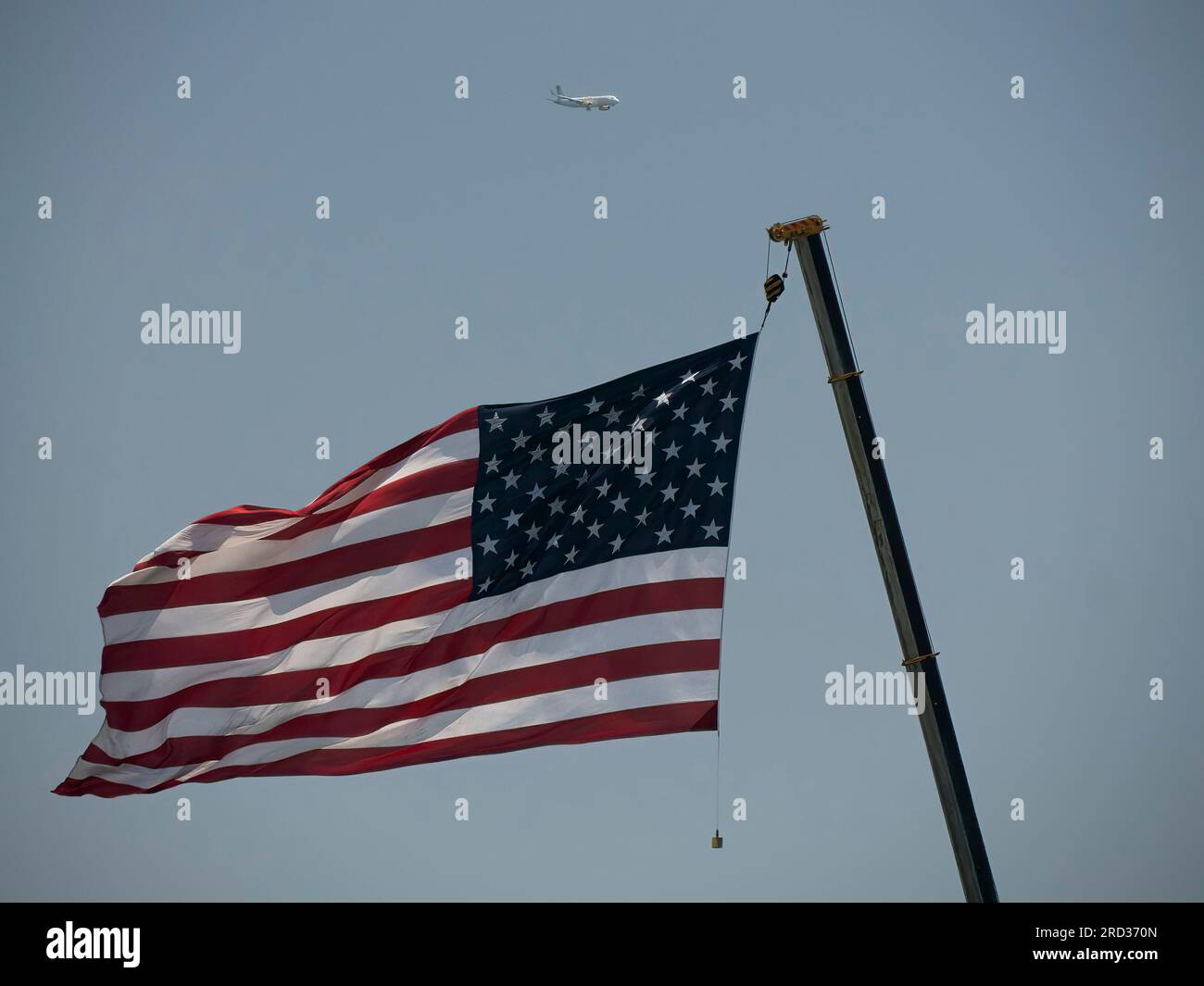 American flag against a blue clear sky and an airplane Stock Photo - Alamy
