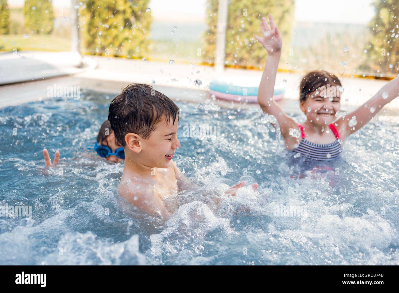 Three small children are swimming in the outdoor pool. Cute kids cuddle ...