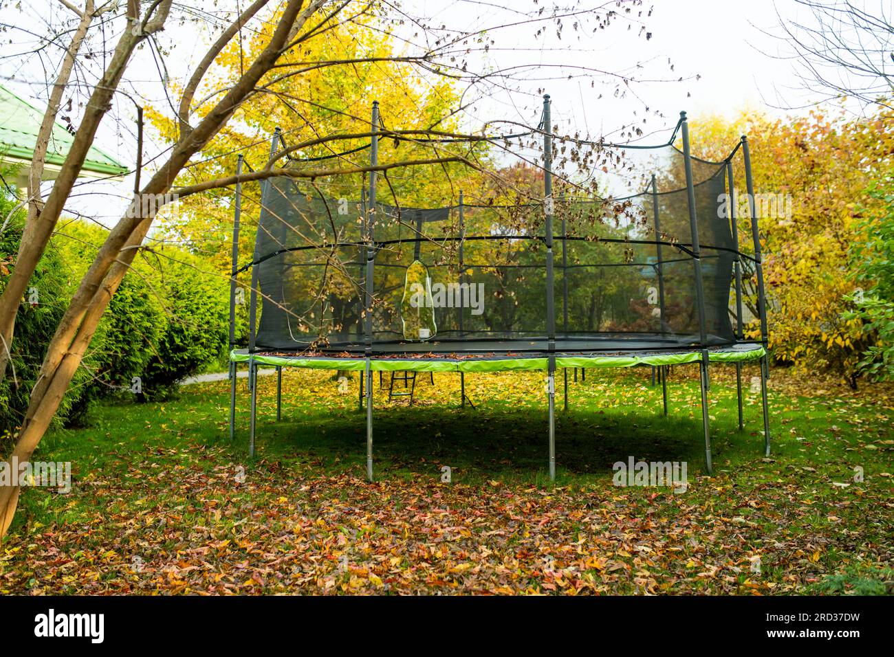 Trampoline at a backyard of family house on late autumn day. Active ...