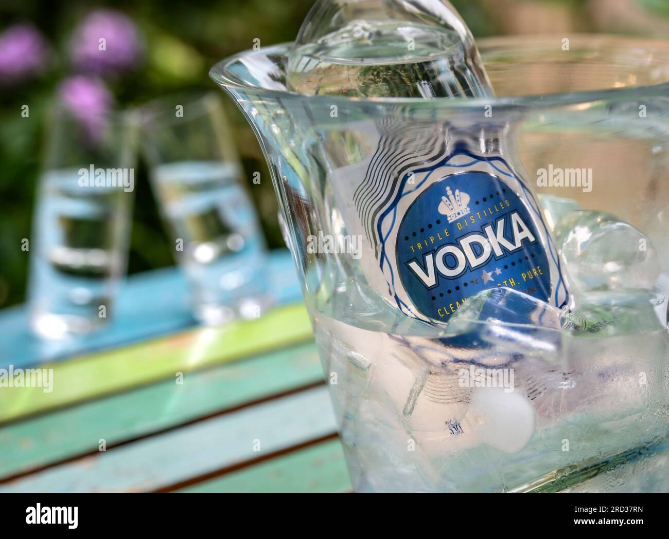 Vodka bottle on ice in crystal drinks cooler with two poured glasses ...