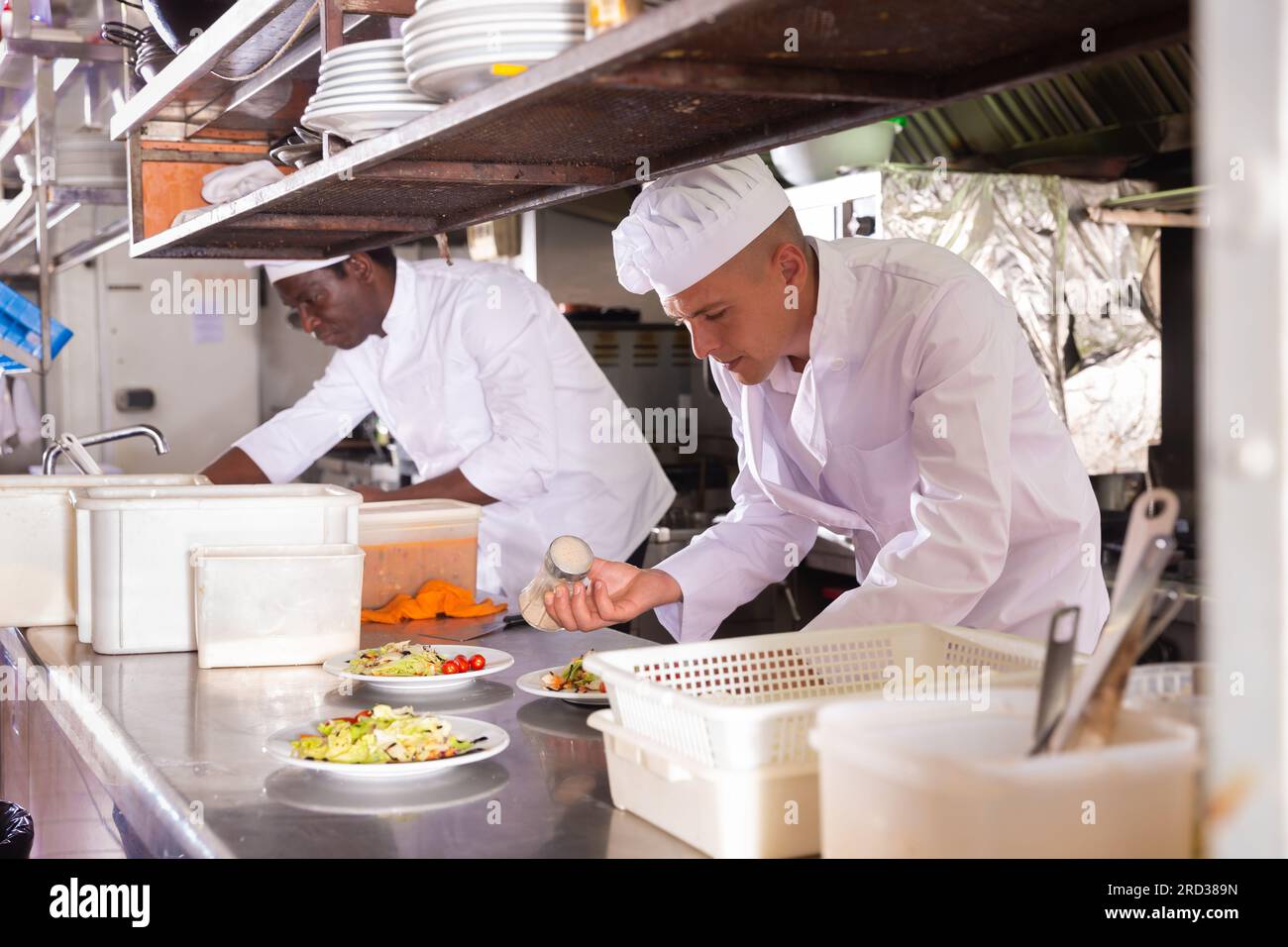 Professional cook working with assistants in restaurant kitchen Stock ...