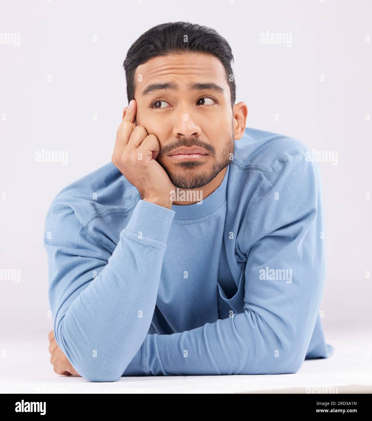 Thinking, remember and young man in a studio resting on his arms with a ...