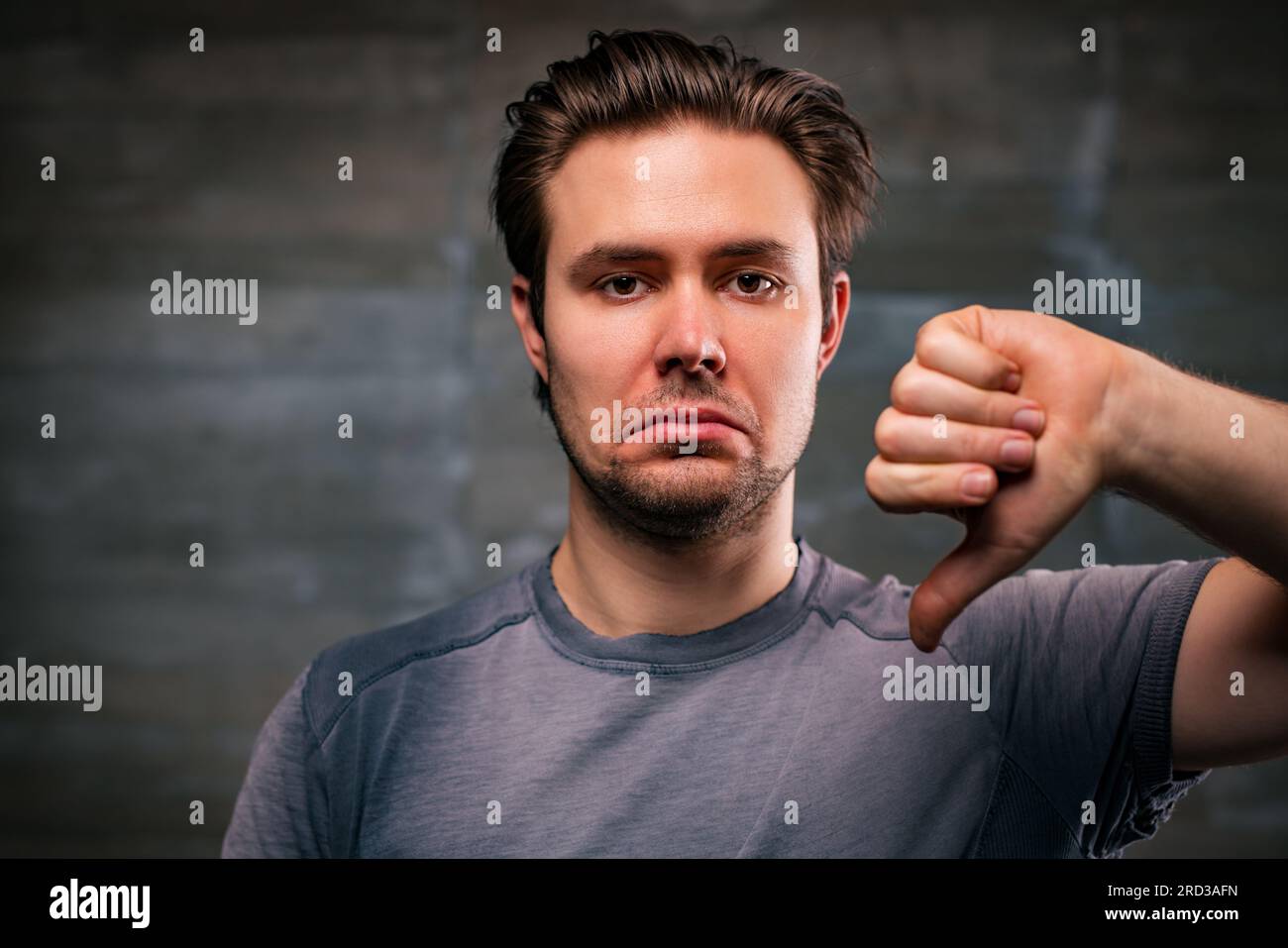 Young handsome man thumb down portrait on gray wall background Stock ...