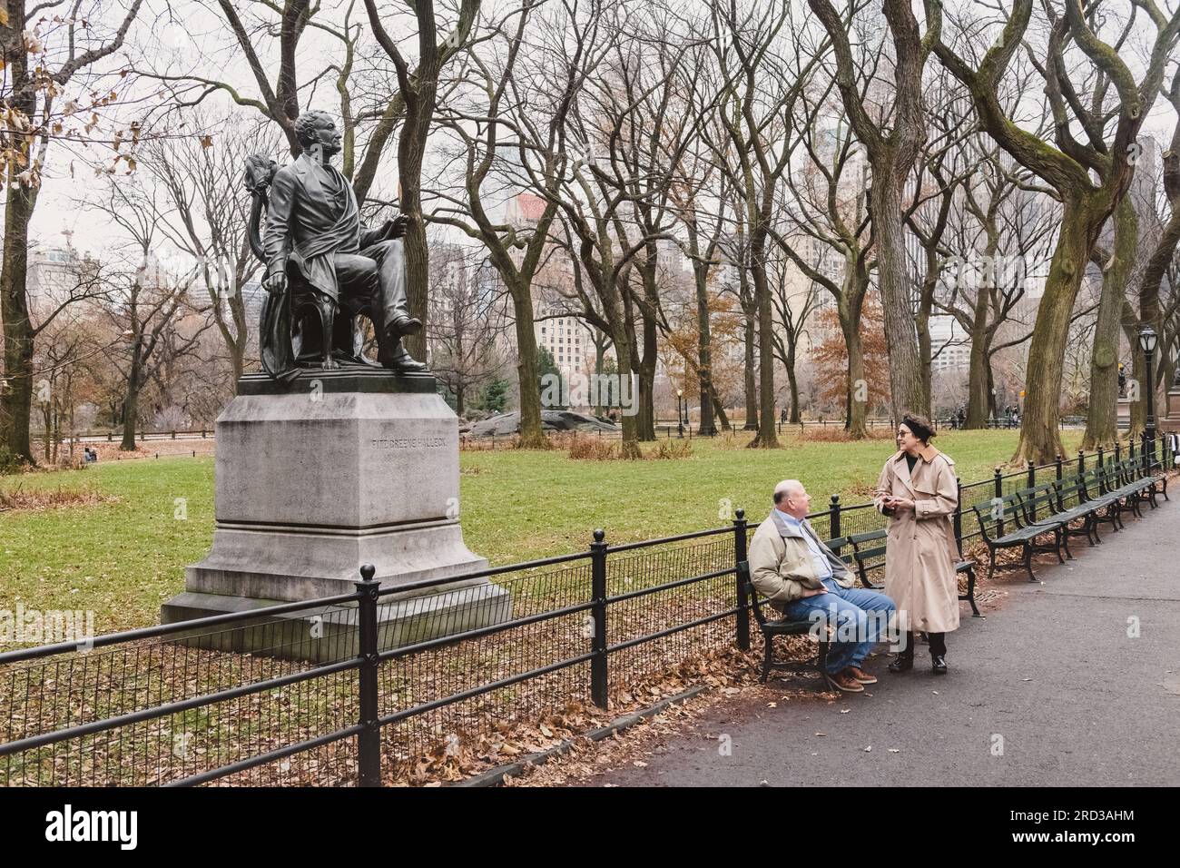 Senior couple chatting on a bench with a statue behind them, Central ...