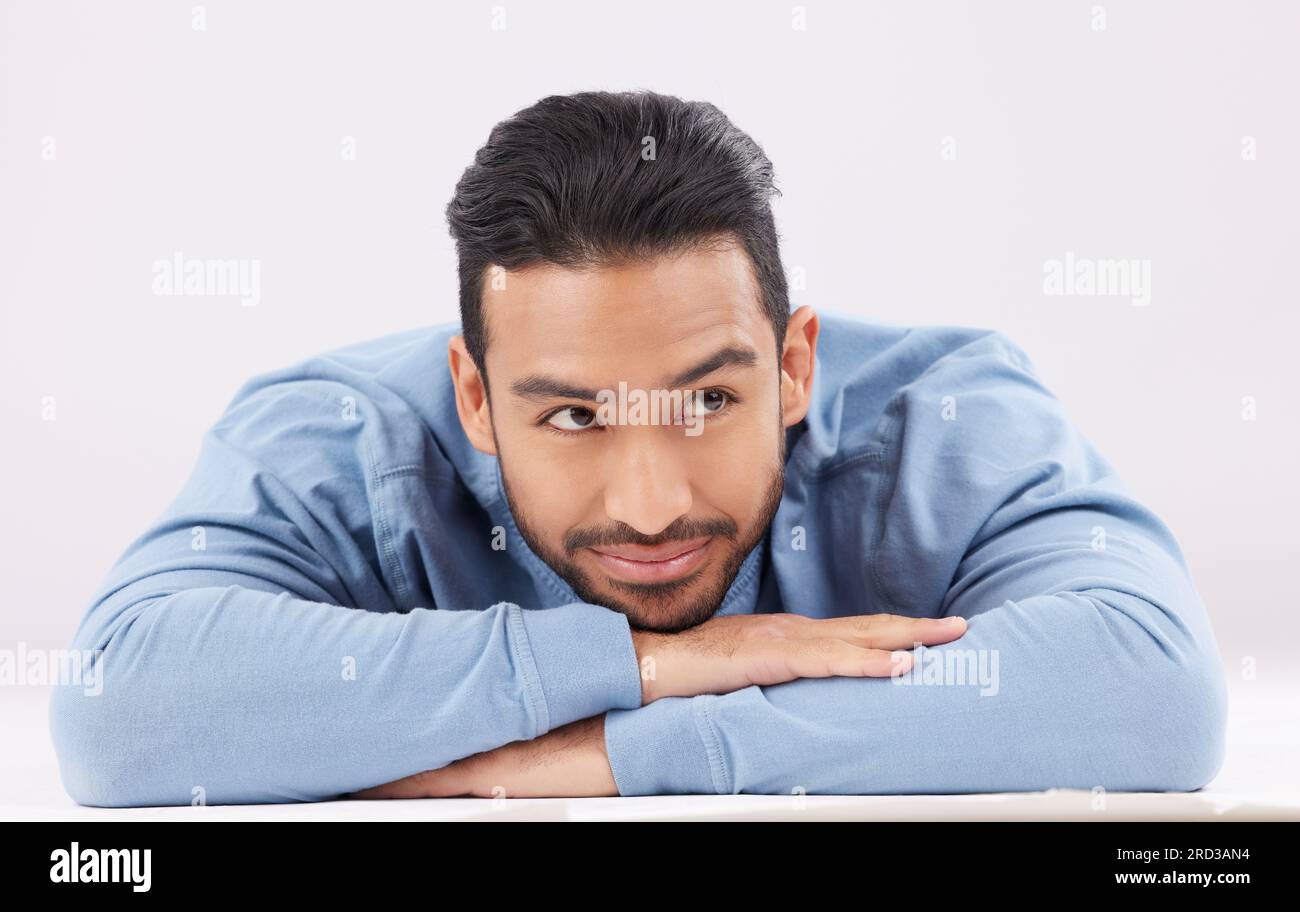 Thinking, dreaming and young man in a studio resting on his arms with a ...
