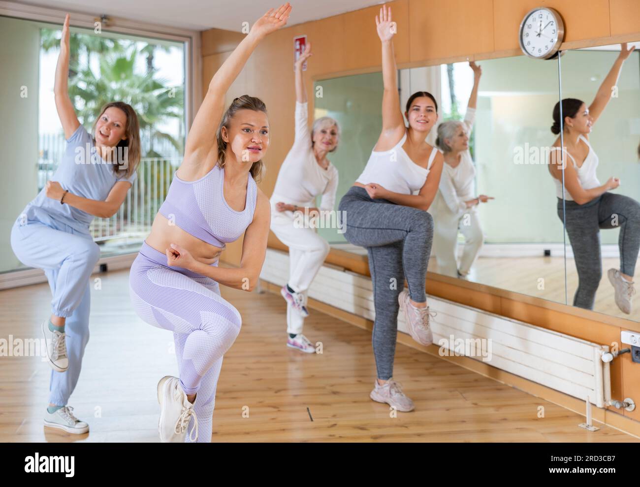 Group of excited young adult women in activewear performing dynamic ...