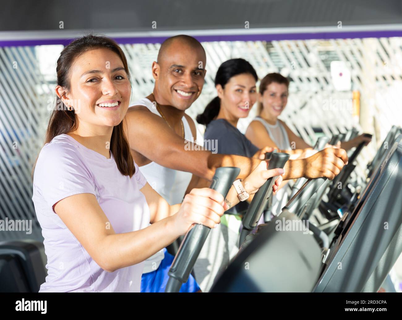 People having running elliptical trainer class in club Stock Photo - Alamy
