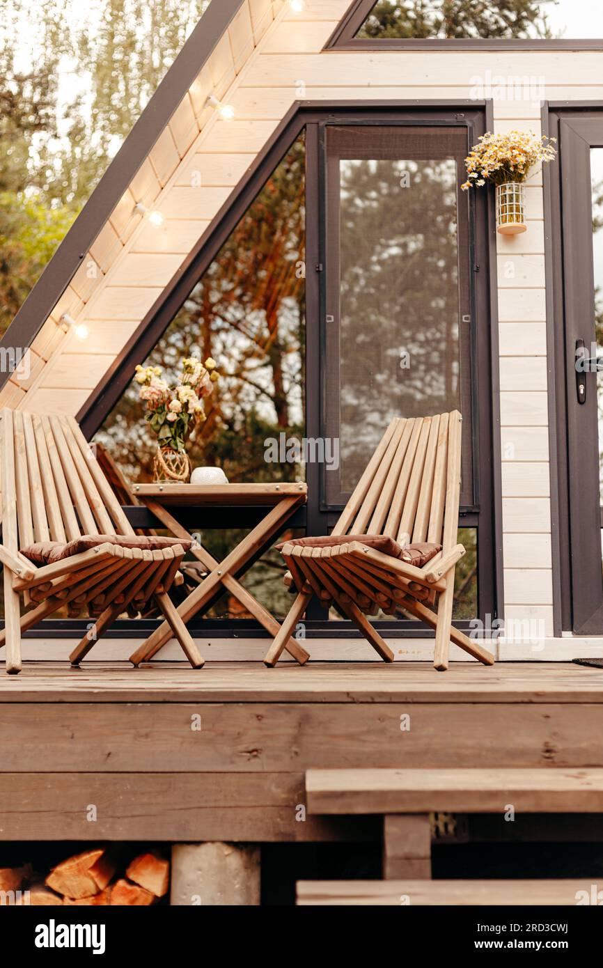 Modern triangle a-frame forest house with terrace, chairs and a table ...