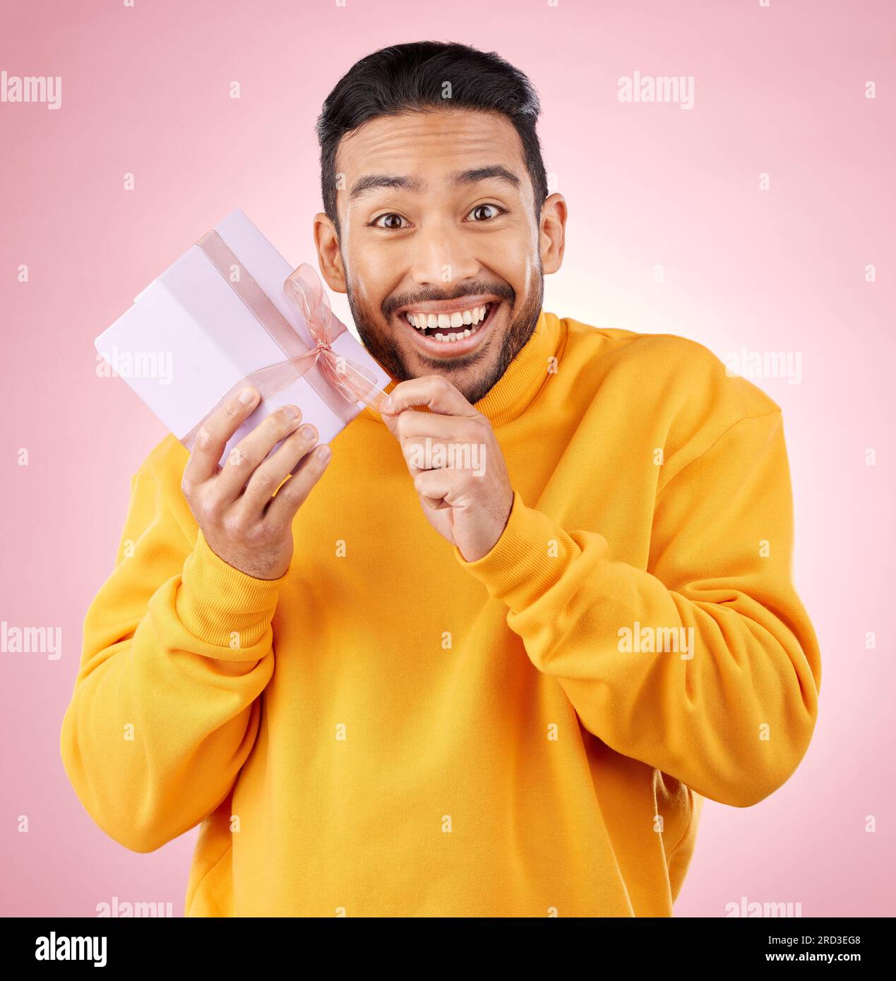 Young man, gift box and studio portrait with excited smile, ribbon and ...