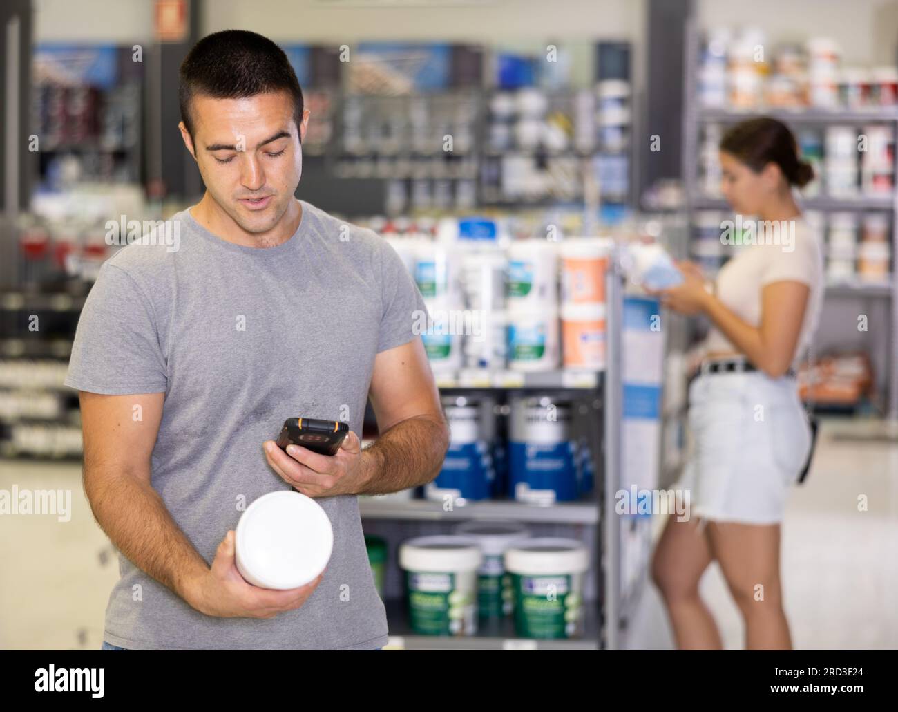 Male shopper scanning a QR code using a mobile phone in hardware store ...