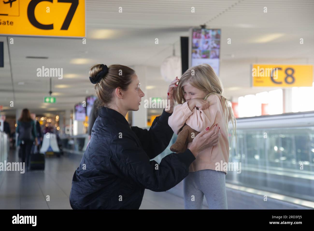 Young woman comforting child lost at the airport who can't find her ...