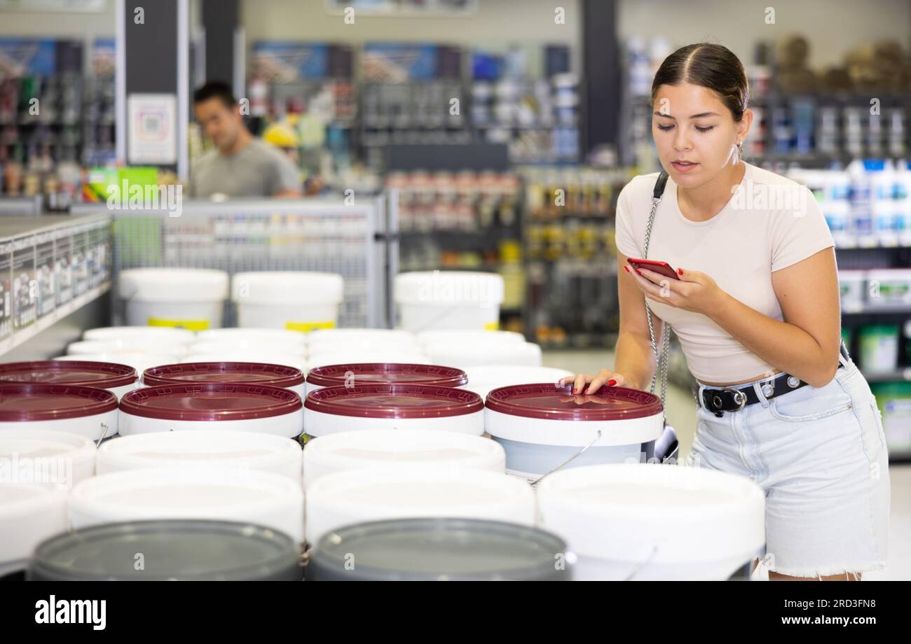 Female shopper scanning a QR code using a mobile phone in hardware ...