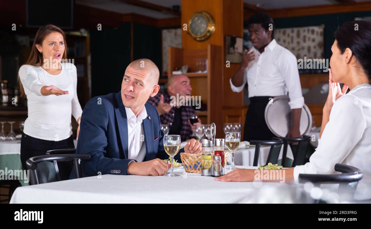 Wife scolding husband spending time with another woman in restaurant ...