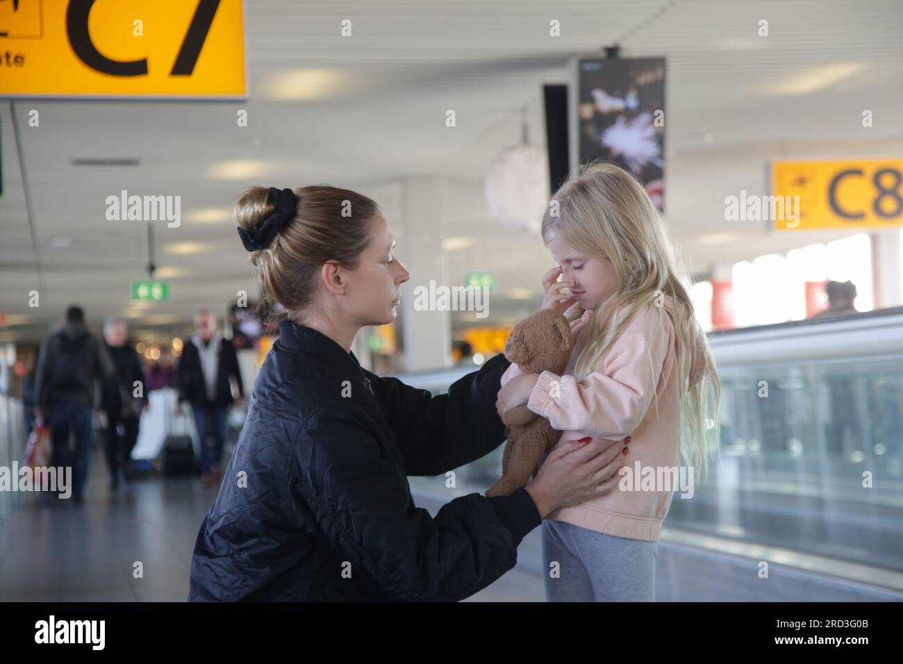Young woman comforting child lost at the airport who can't find her ...