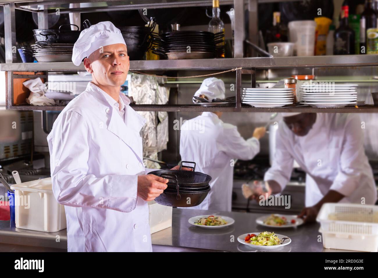 Professional cook working with assistants in restaurant kitchen Stock ...