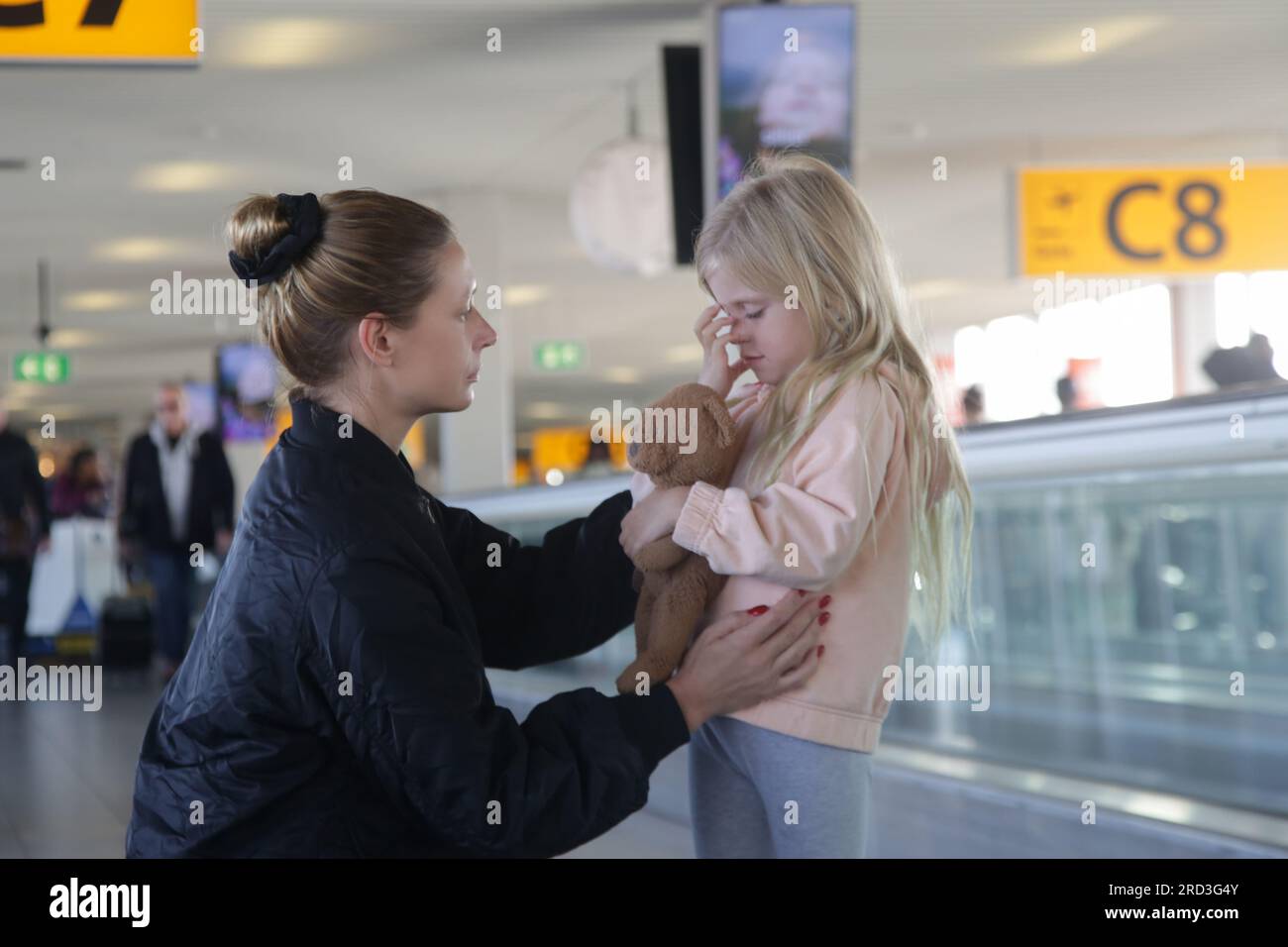Young woman comforting child lost at the airport who can't find her ...