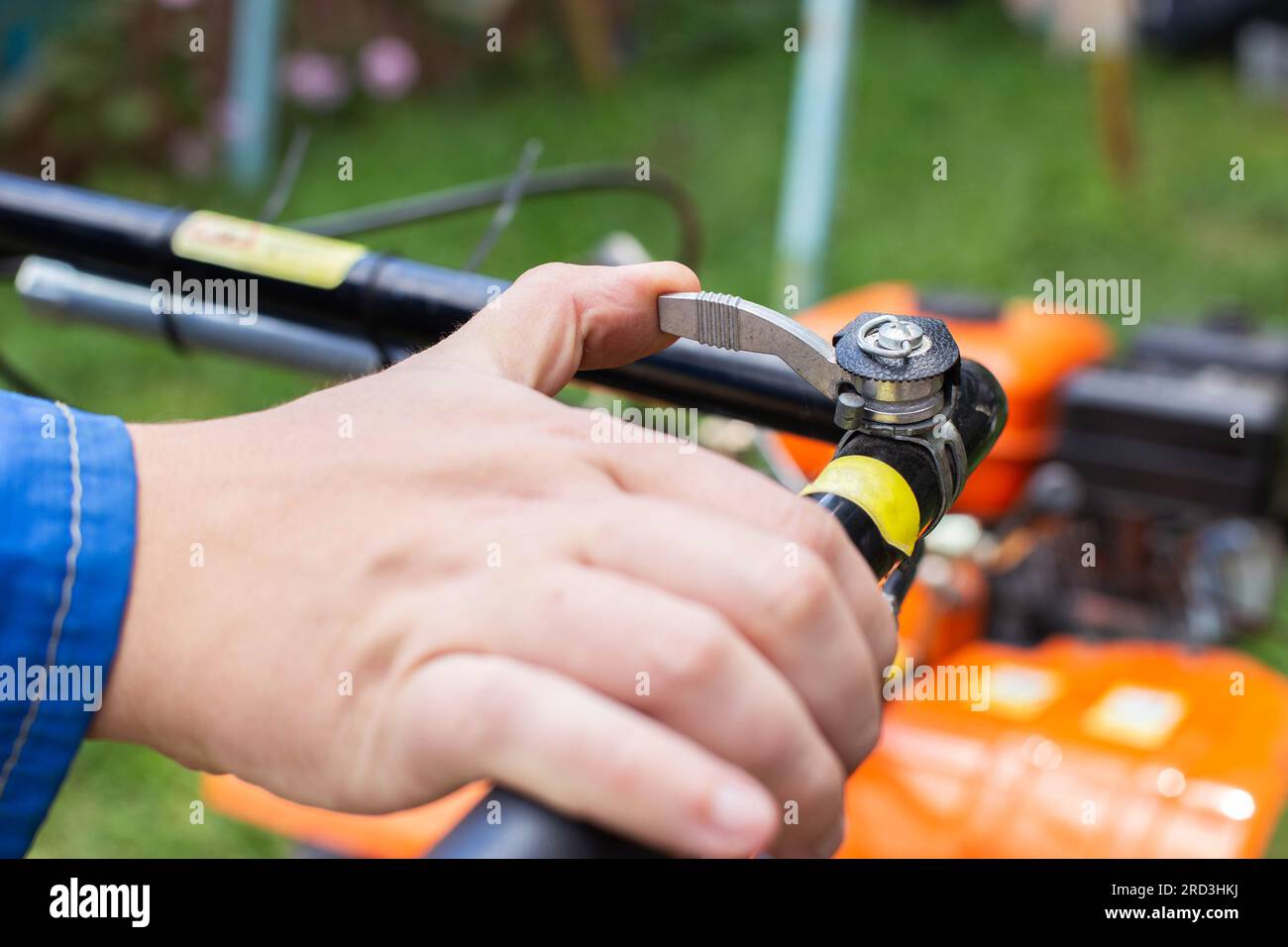 A man adjusts the throttle on the handle of a walk-behind tractor ...