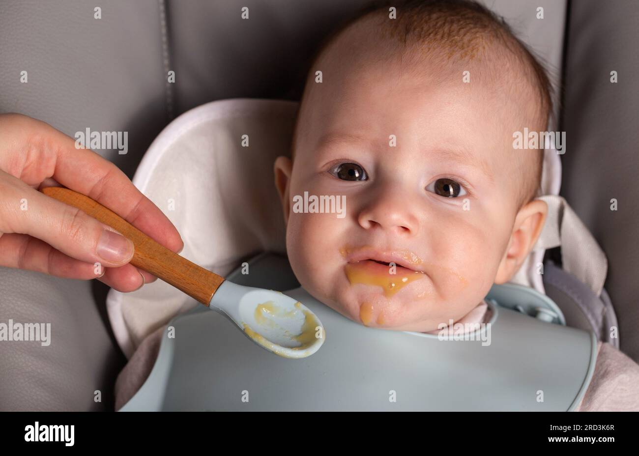 A 6-month-old baby tries porridge for the first time. Feeding babies ...