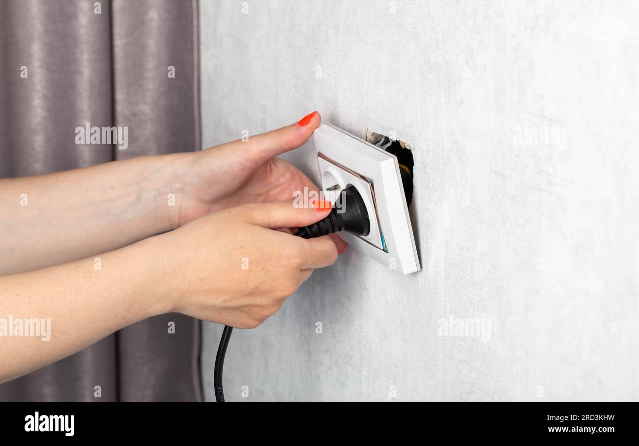 The girl incorrectly removes the electric plug from the socket and ...