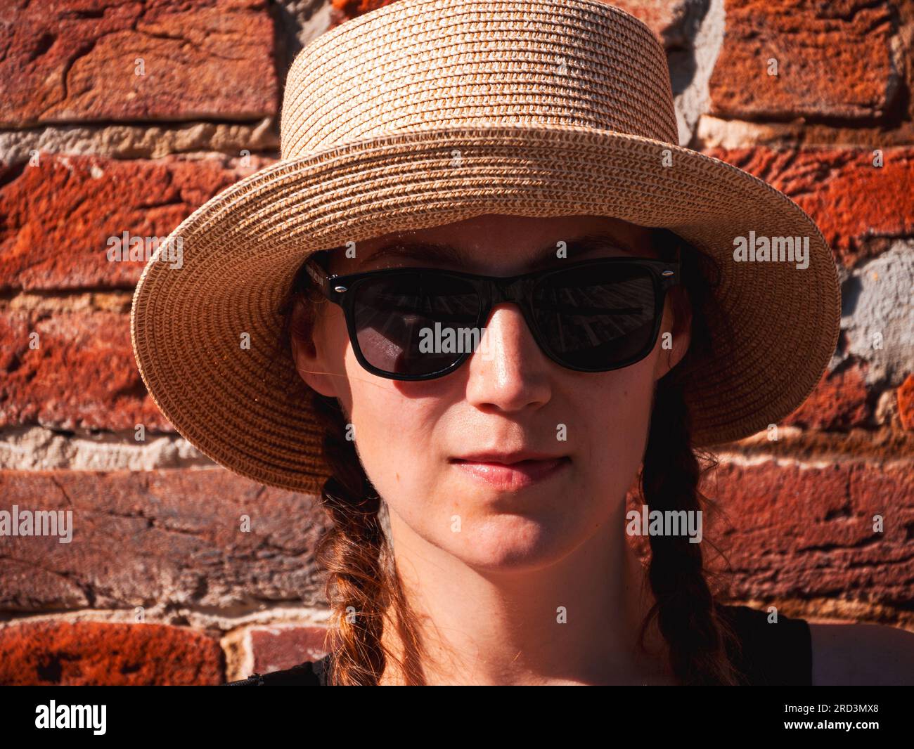 Young woman in straw hat portrait on red brick wall urban background ...