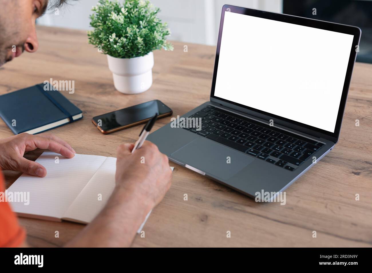 View from back of man using laptop and writing in notebook. modern ...