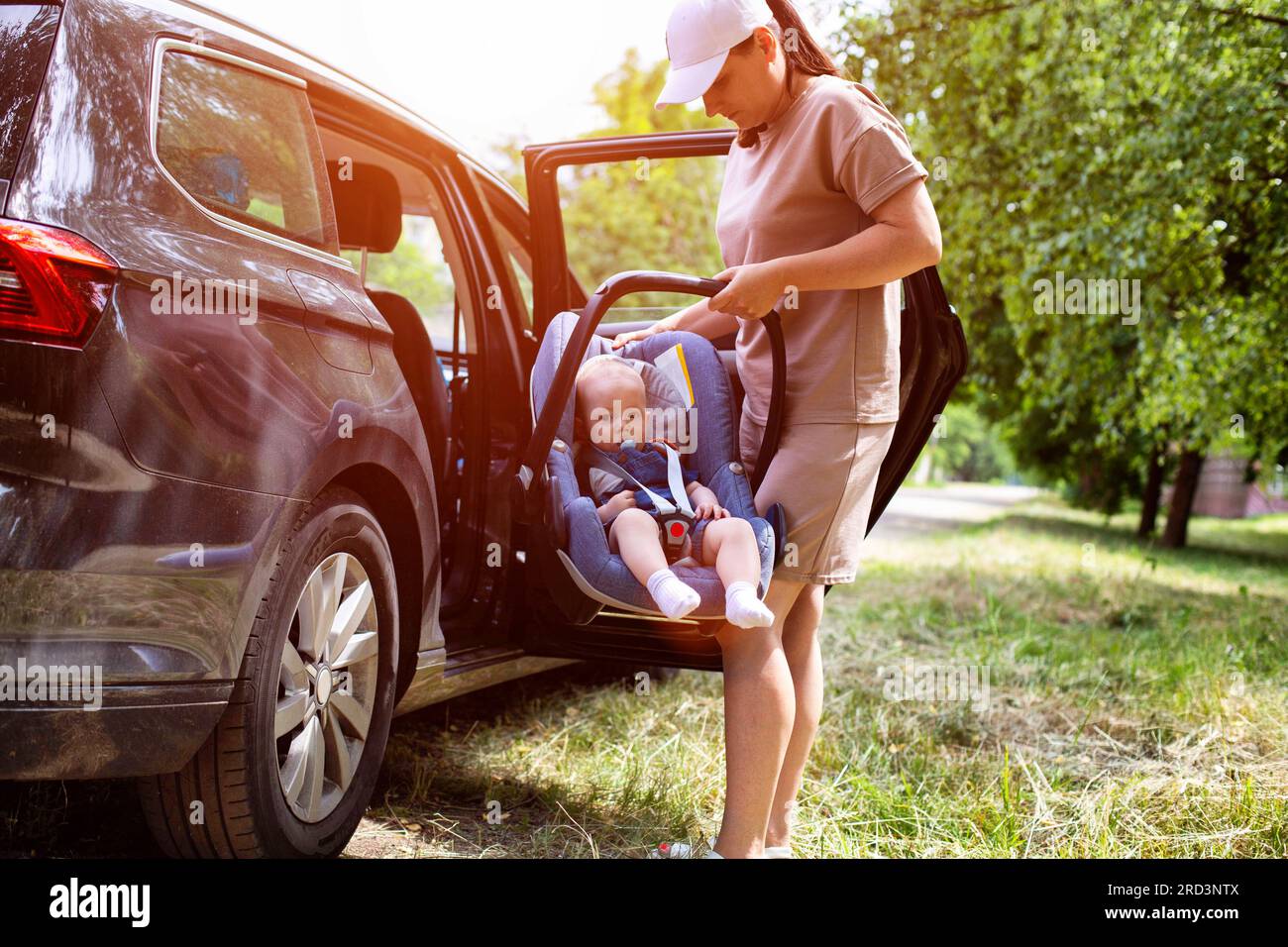 The mother puts the infant car seat with the child in the car. The ...