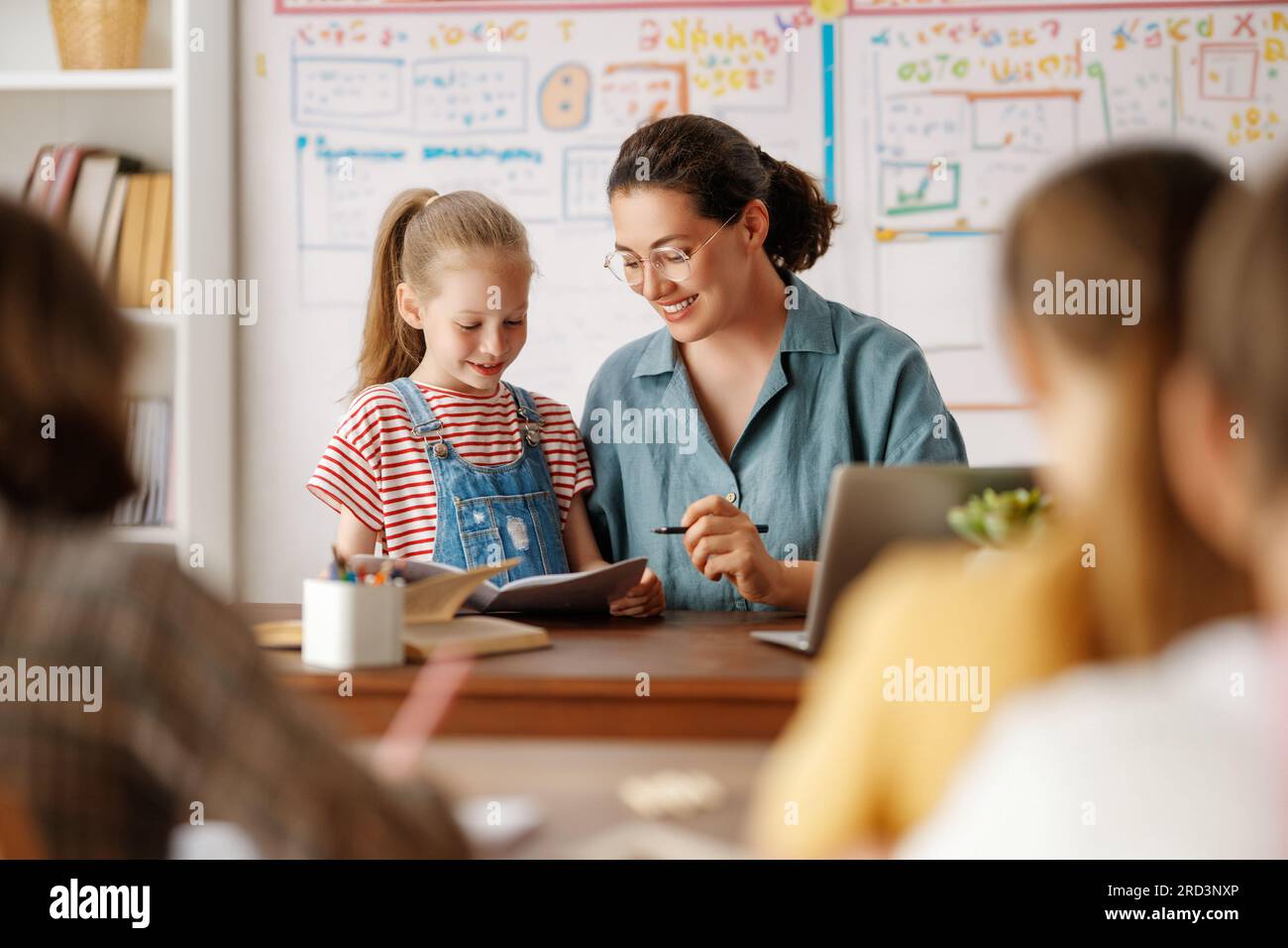 Happy kids and teacher at school. Woman and children are talking in the ...