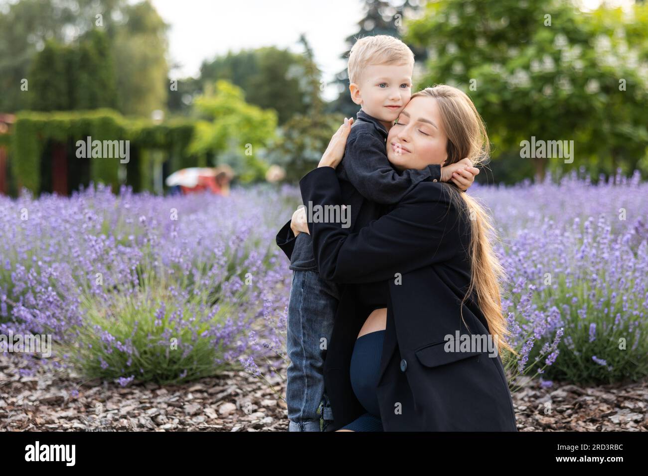 Pregnant mother and her little son spending time together in the park ...